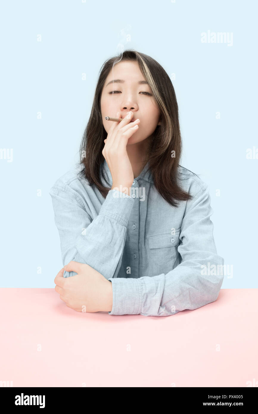 Handsome young korean women smoking cigar while sitting at table at ...