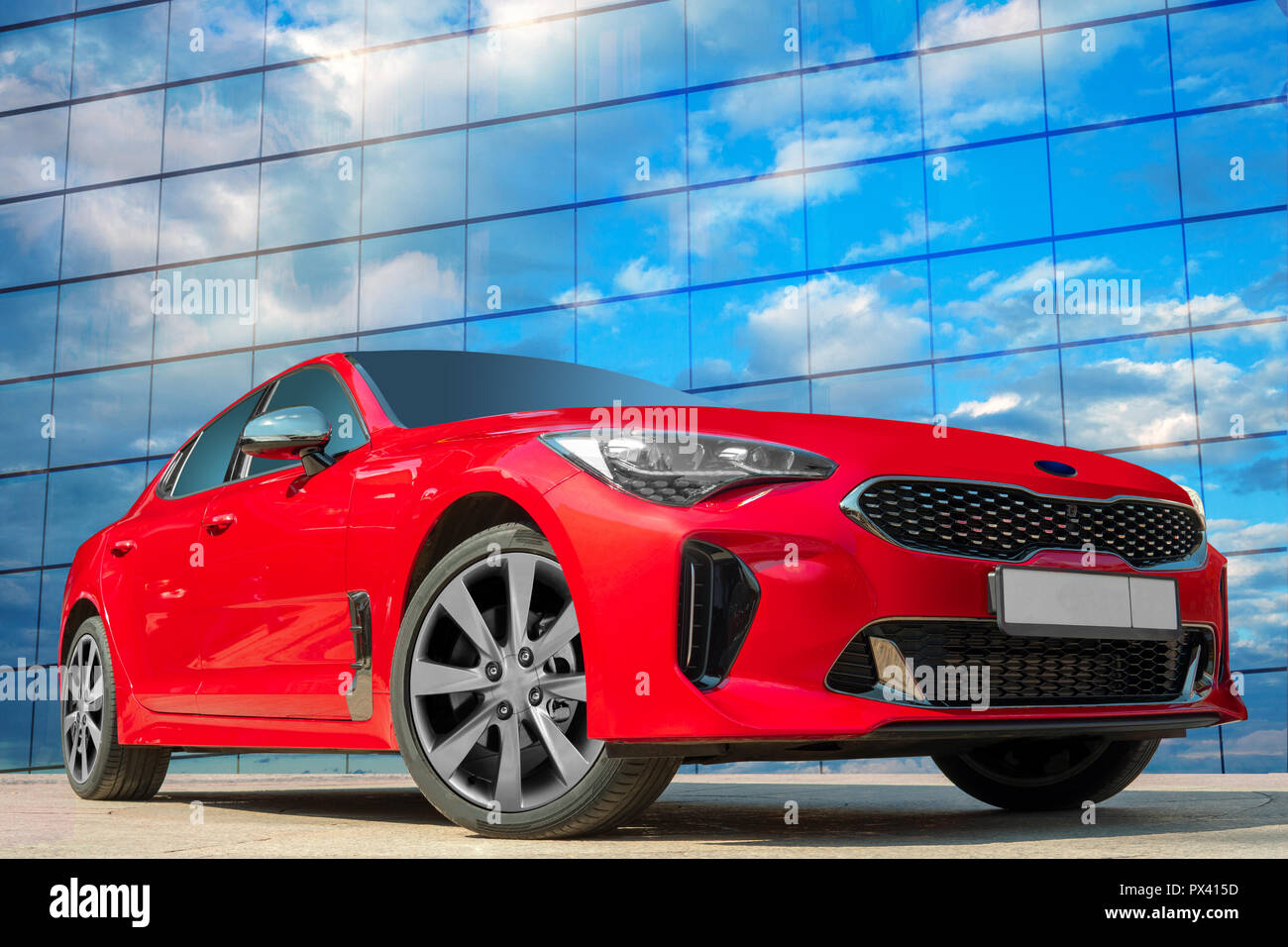 Red car on a blue sky background with white clouds. A stylish, modern ...