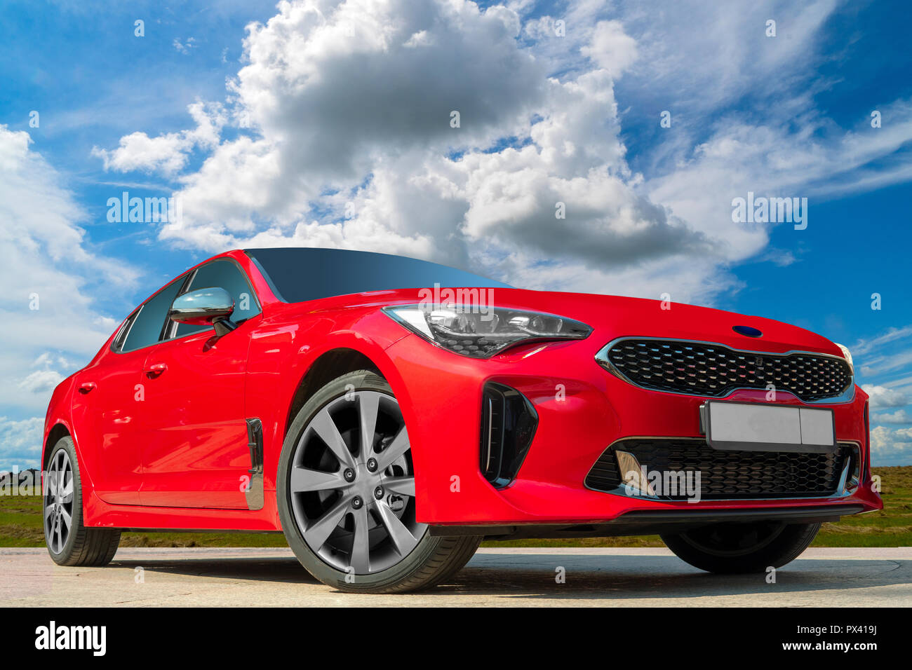 Red car on a blue sky background with white clouds. A stylish, modern ...