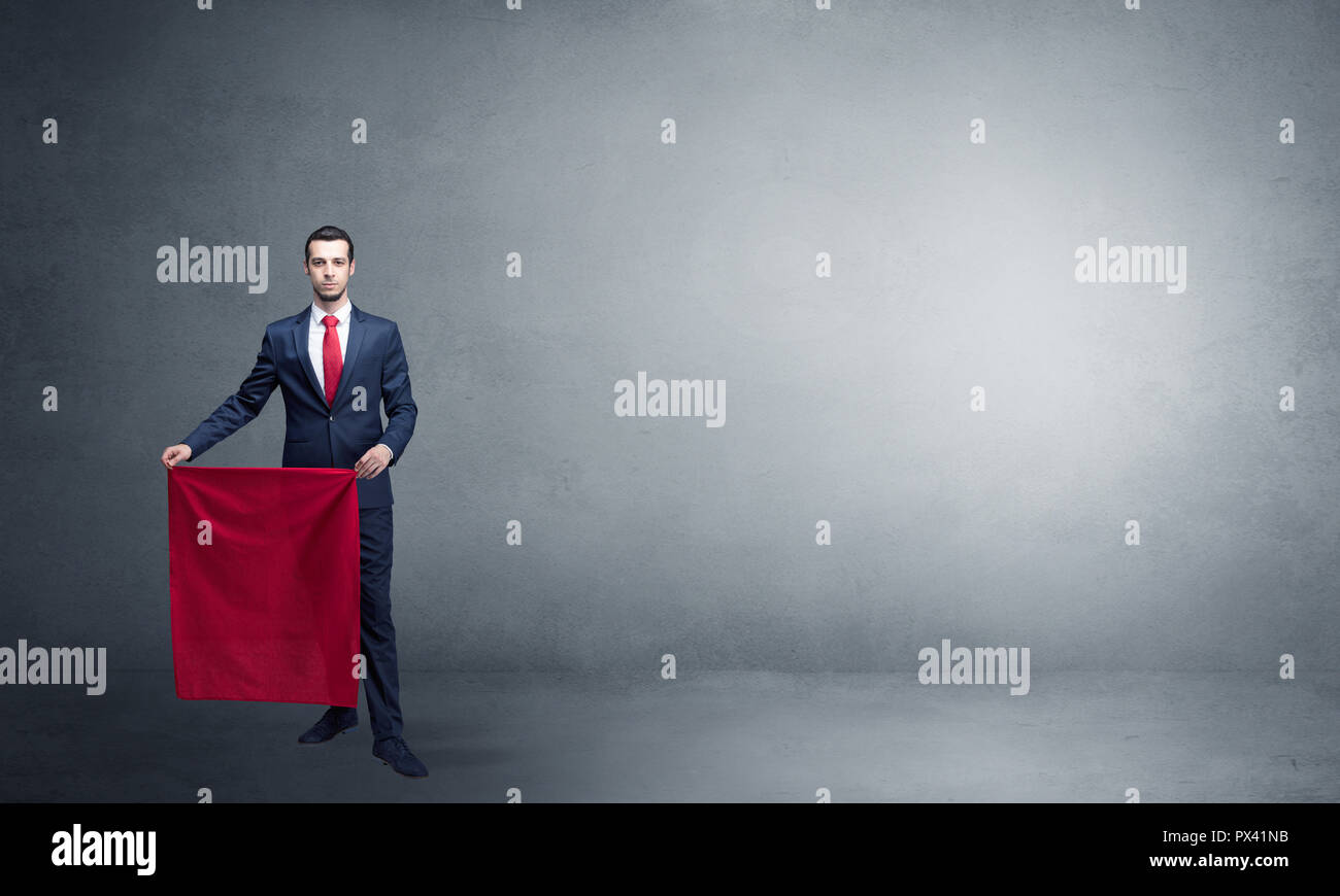 Businessman standing with red toreador cloth in his hand in an empty ...