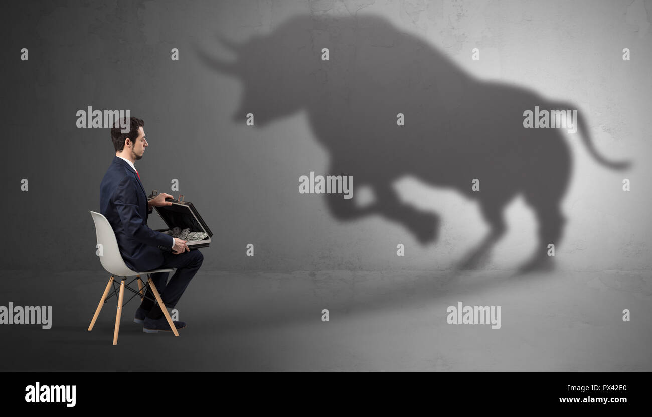 Humble businessman staying and offering stuffs to a huge angry bull ...