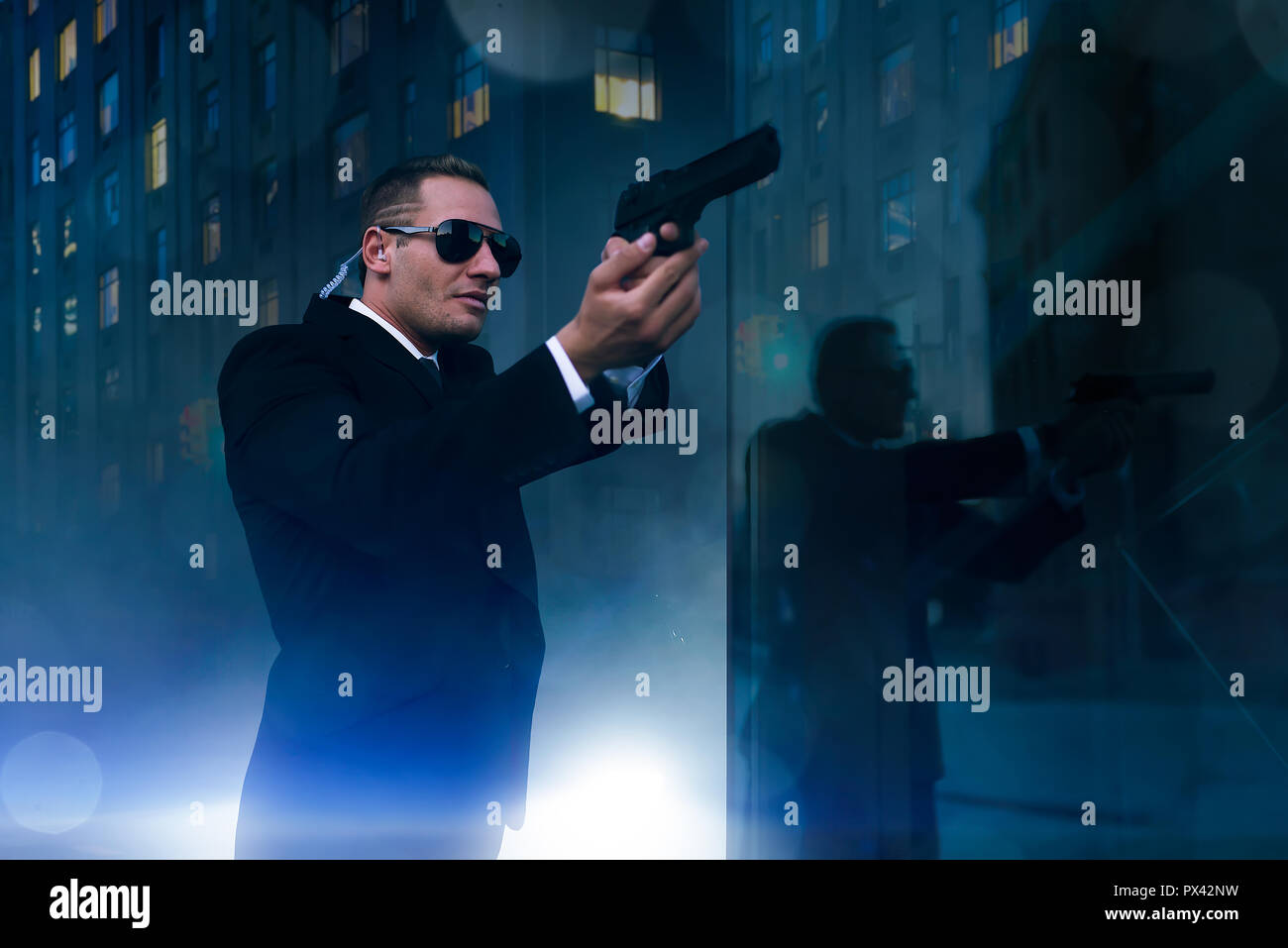 Bodyguard with security earpiece and gun in hands Stock Photo - Alamy