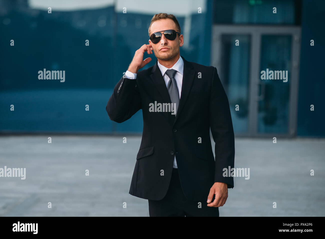 Male bodyguard uses security earpiece outdoors Stock Photo - Alamy
