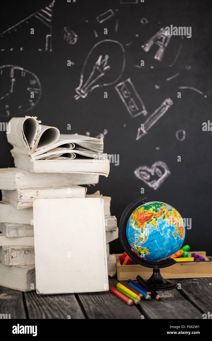 Back to school, stack of books and school supplies on blackboard ...
