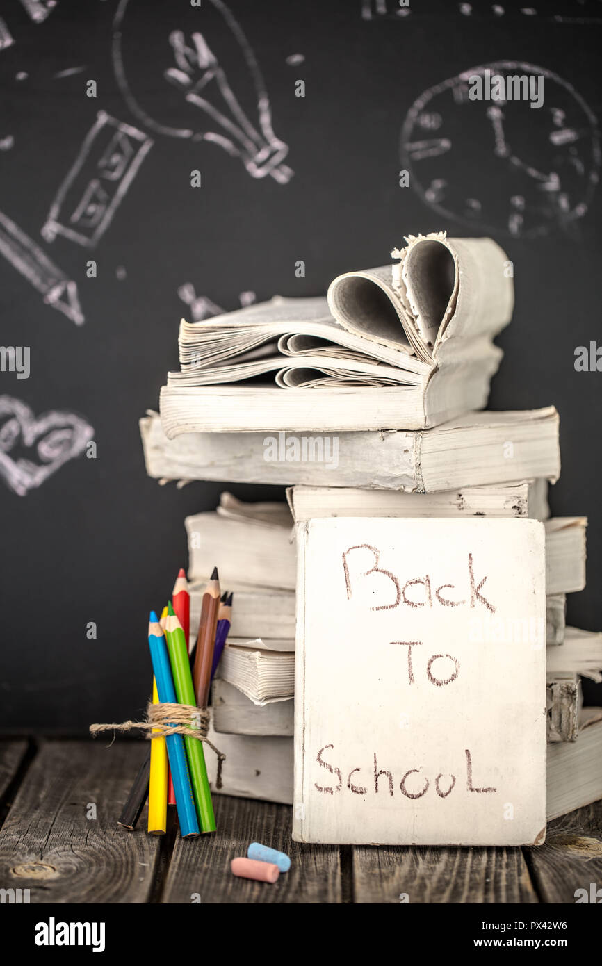 Back to school, stack of books and school supplies on blackboard ...