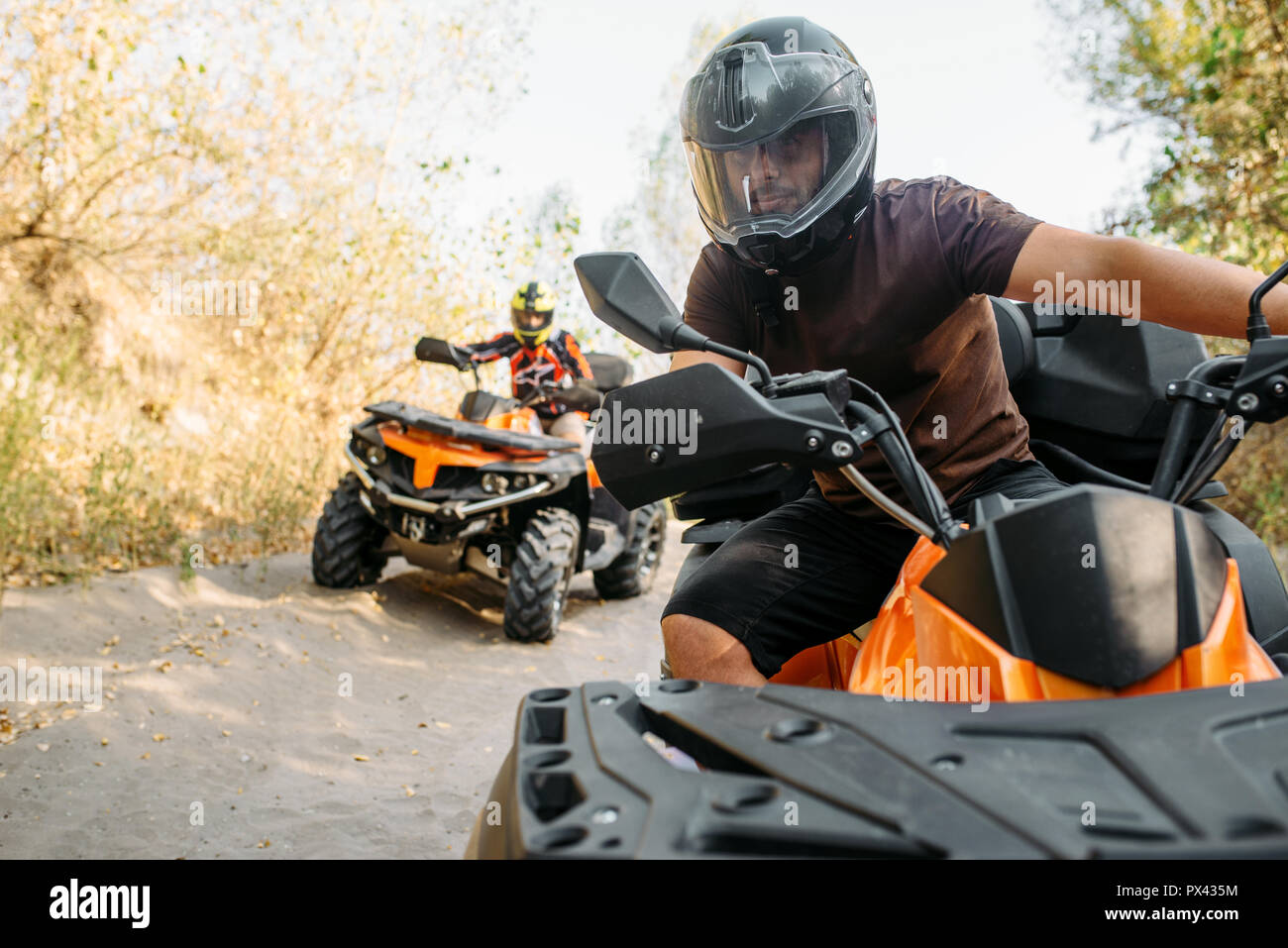 Two quad bike riders travels in forest, front view Stock Photo - Alamy