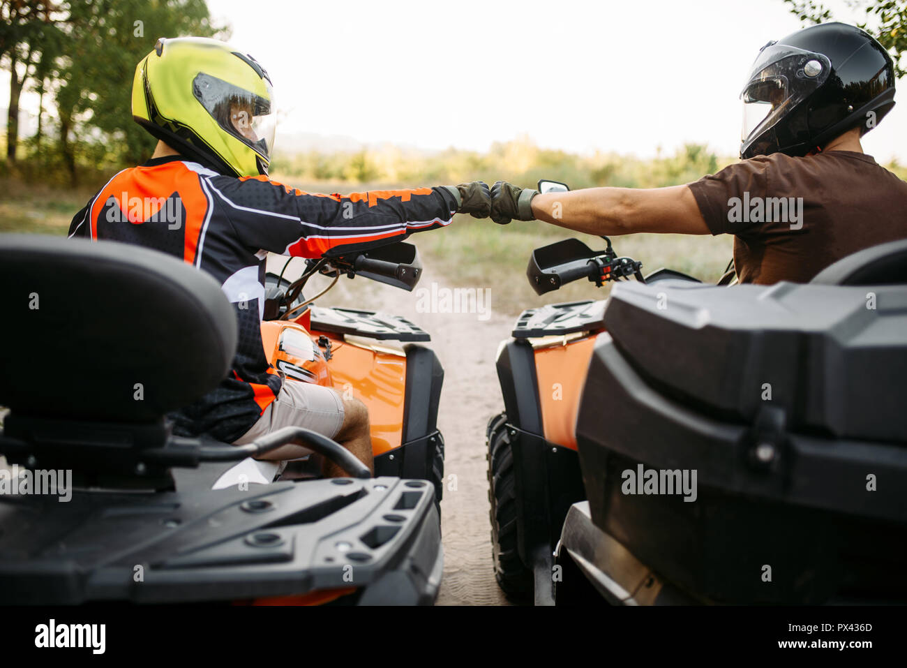 Two atv riders hits fists for good luck, back view Stock Photo - Alamy