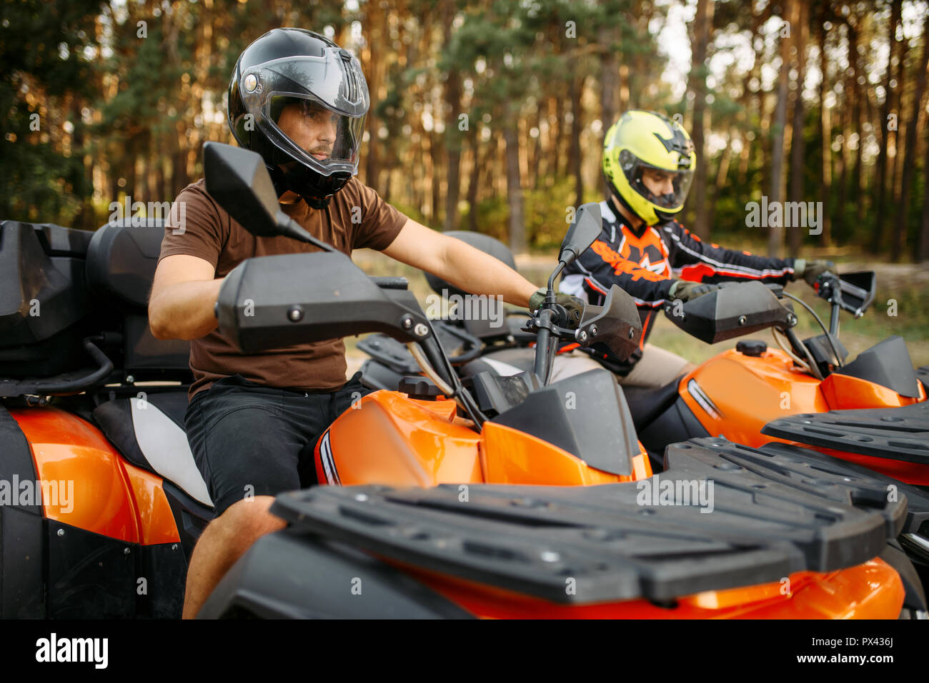 Two quad bike riders in helmets closeup, side view Stock Photo - Alamy