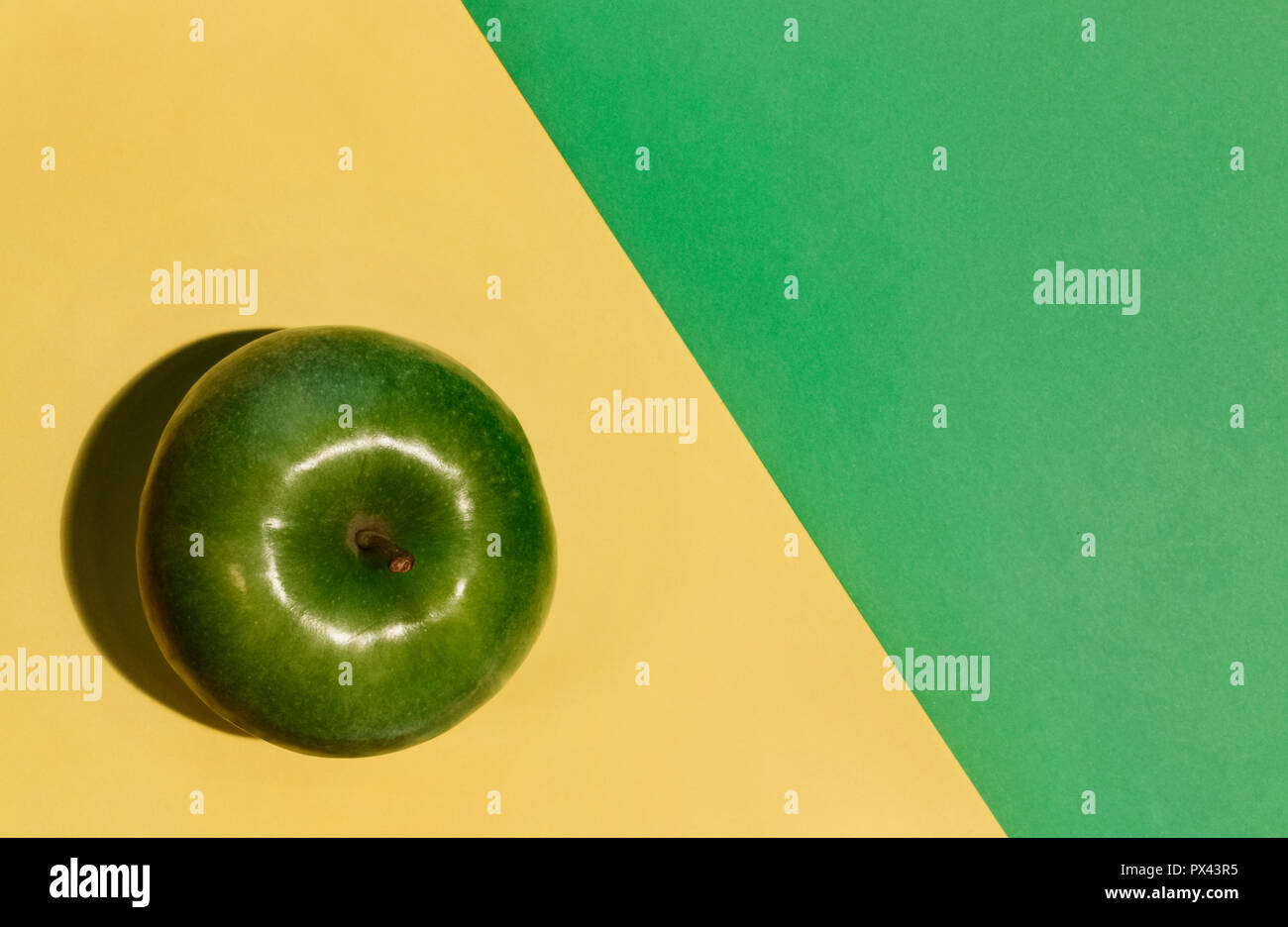 One green apple on a yellow and green background , top view , studio ...