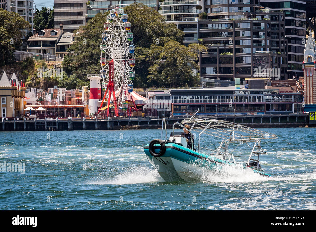 Small speed boat travelling at speed in front of Luna Park Ferris Wheel ...