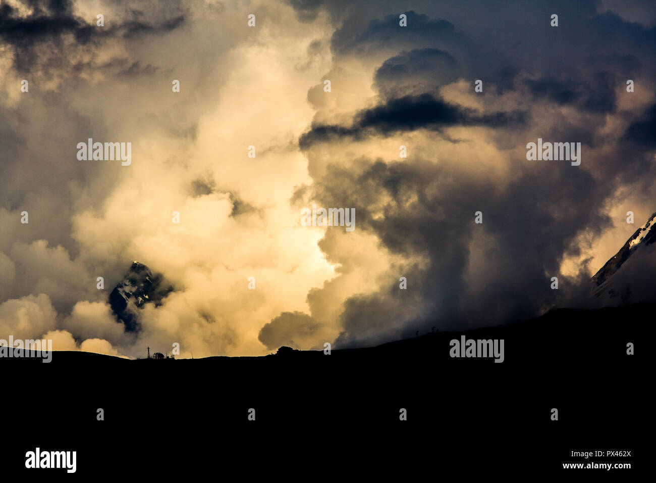 Dramatic silhouette of hills against a stormy cloud-filled sky at dusk ...