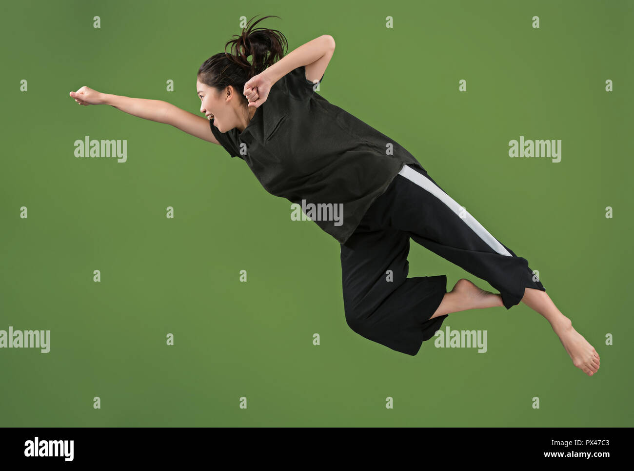 I am happy. Mid-air shot of pretty smiling young woman jumping and ...