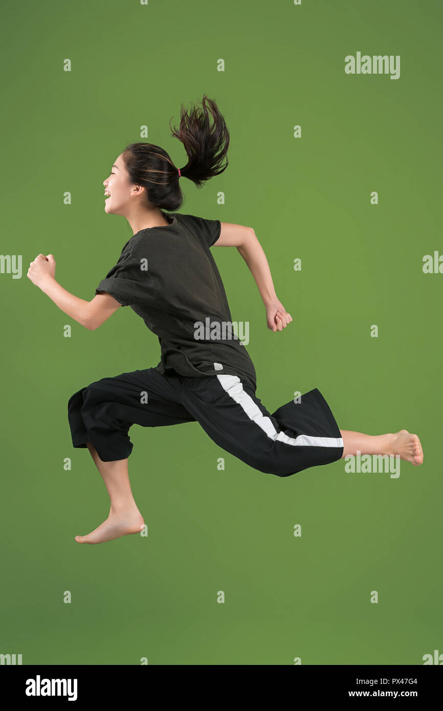 I am happy. Mid-air shot of pretty smiling young woman jumping and ...