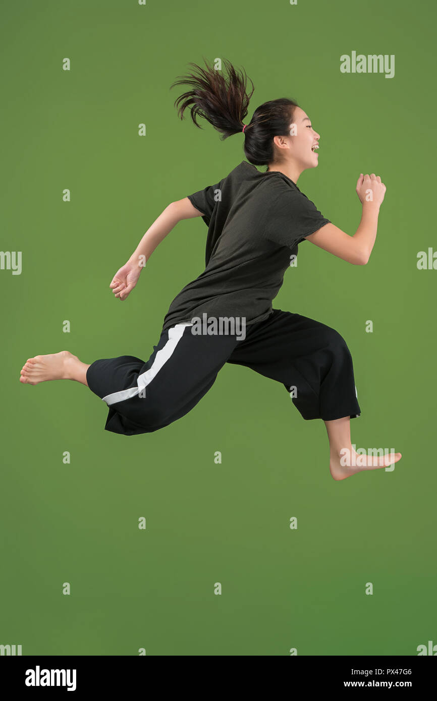 I am happy. Mid-air shot of pretty smiling young woman jumping and ...