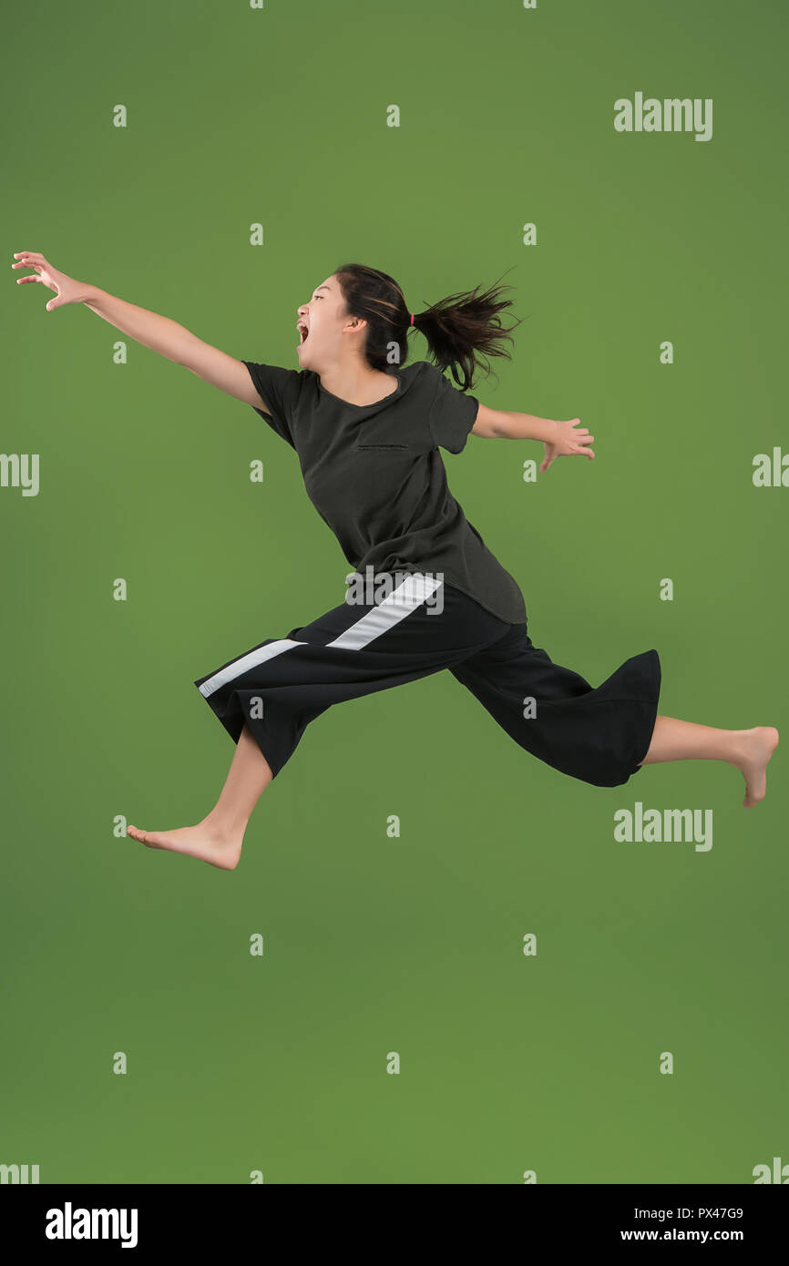 I am happy. Mid-air shot of pretty smiling young woman jumping and ...