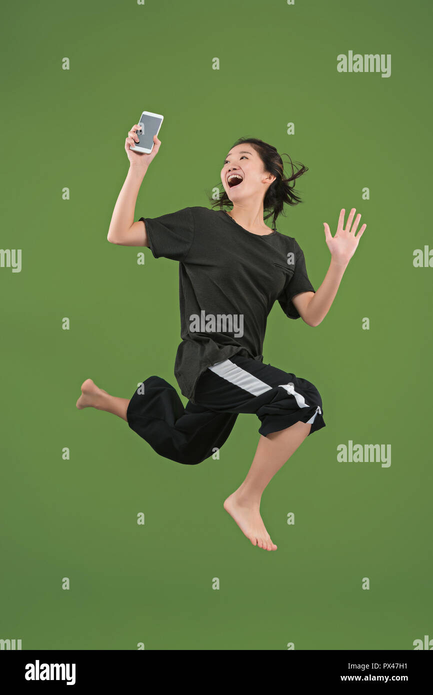 I am happy. Mid-air shot of pretty smiling young woman jumping and ...