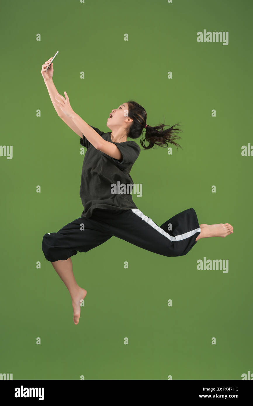 I am happy. Mid-air shot of pretty smiling young woman jumping and ...