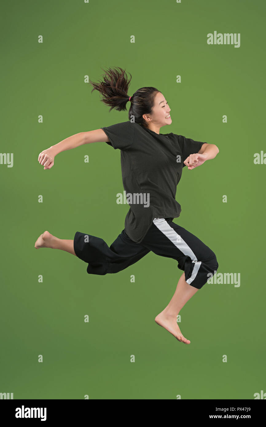 I am happy. Mid-air shot of pretty smiling young woman jumping and ...