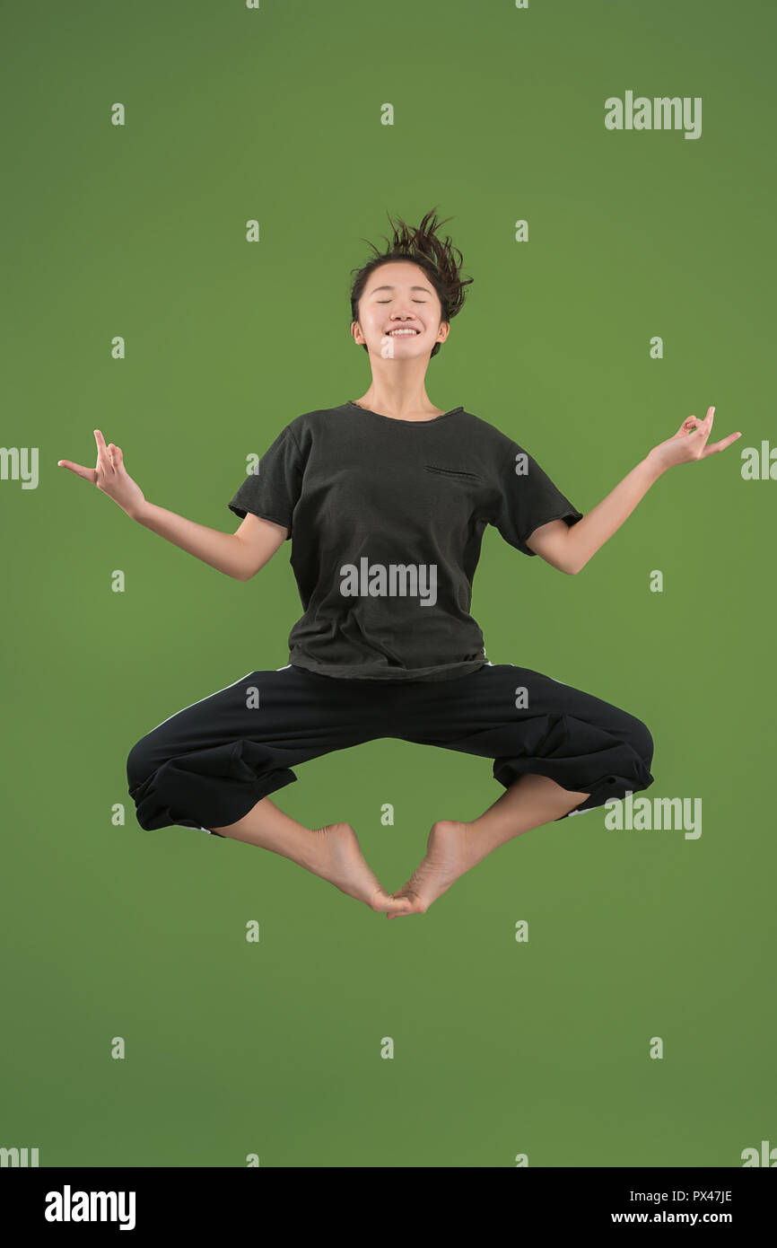 I am happy. Mid-air shot of pretty smiling young woman jumping and ...