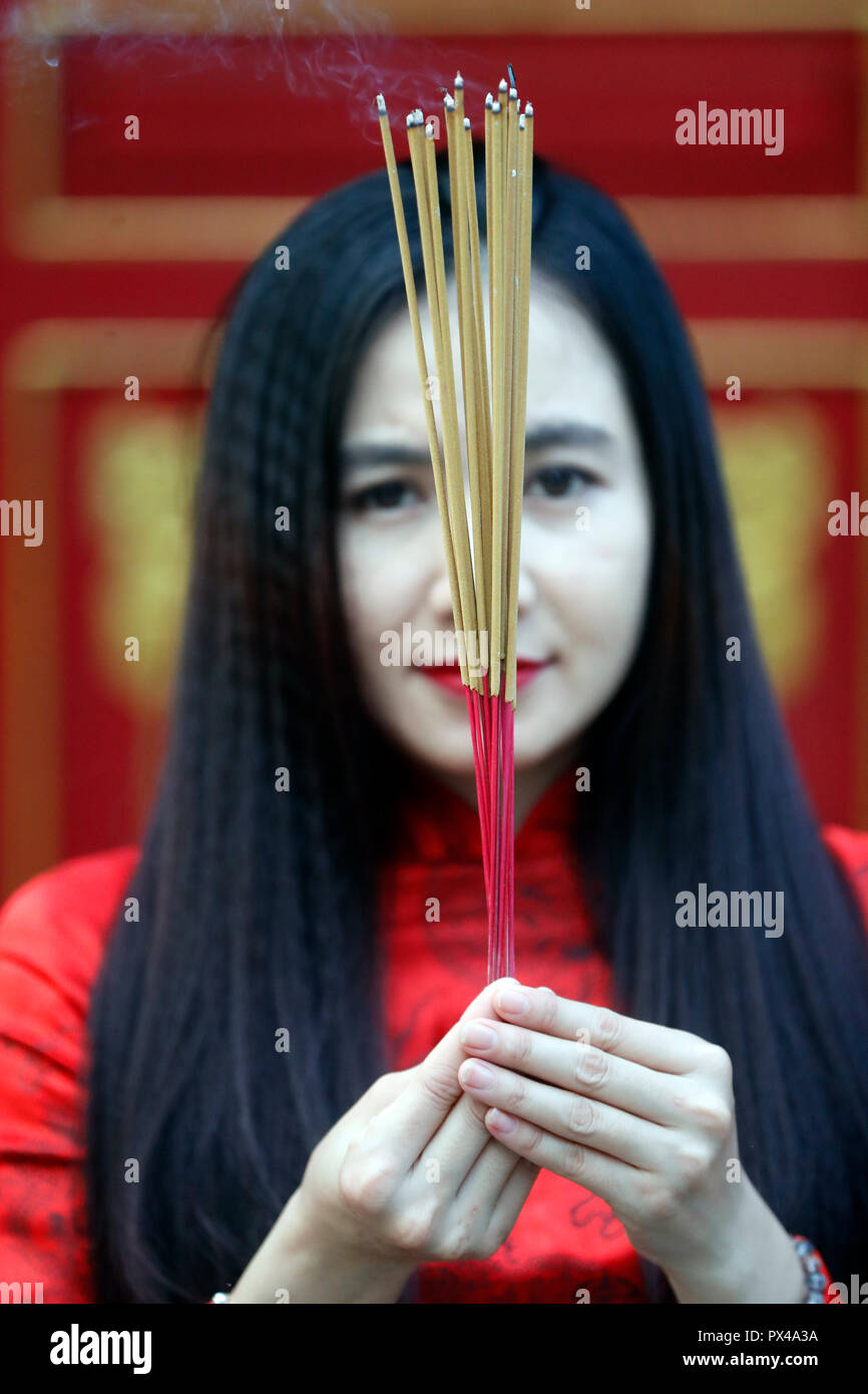 Vietnamese woman in red traditional long dress Ao Dai praying with ...