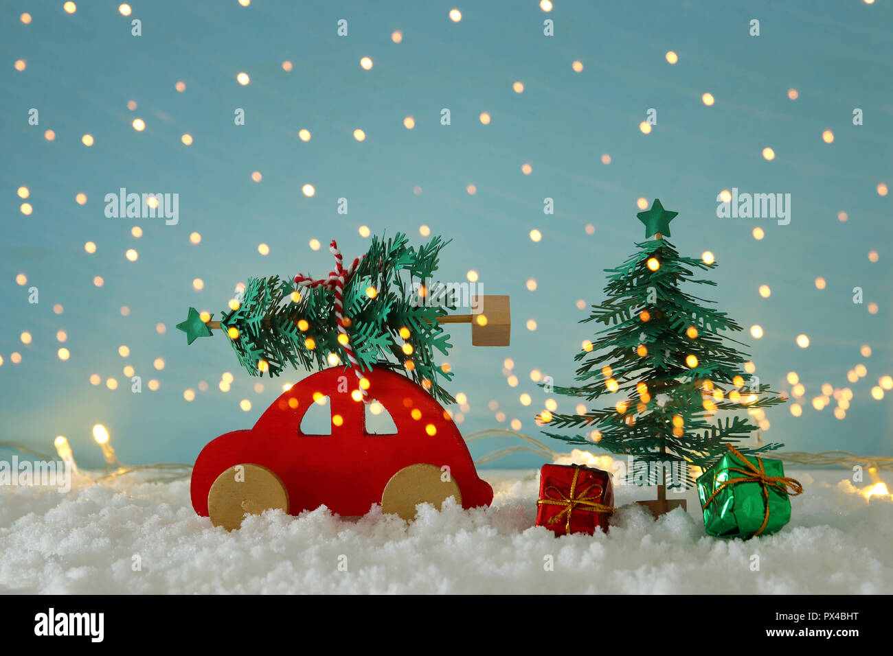 Red wooden car carrying a christmas tree over snow in front of blue ...