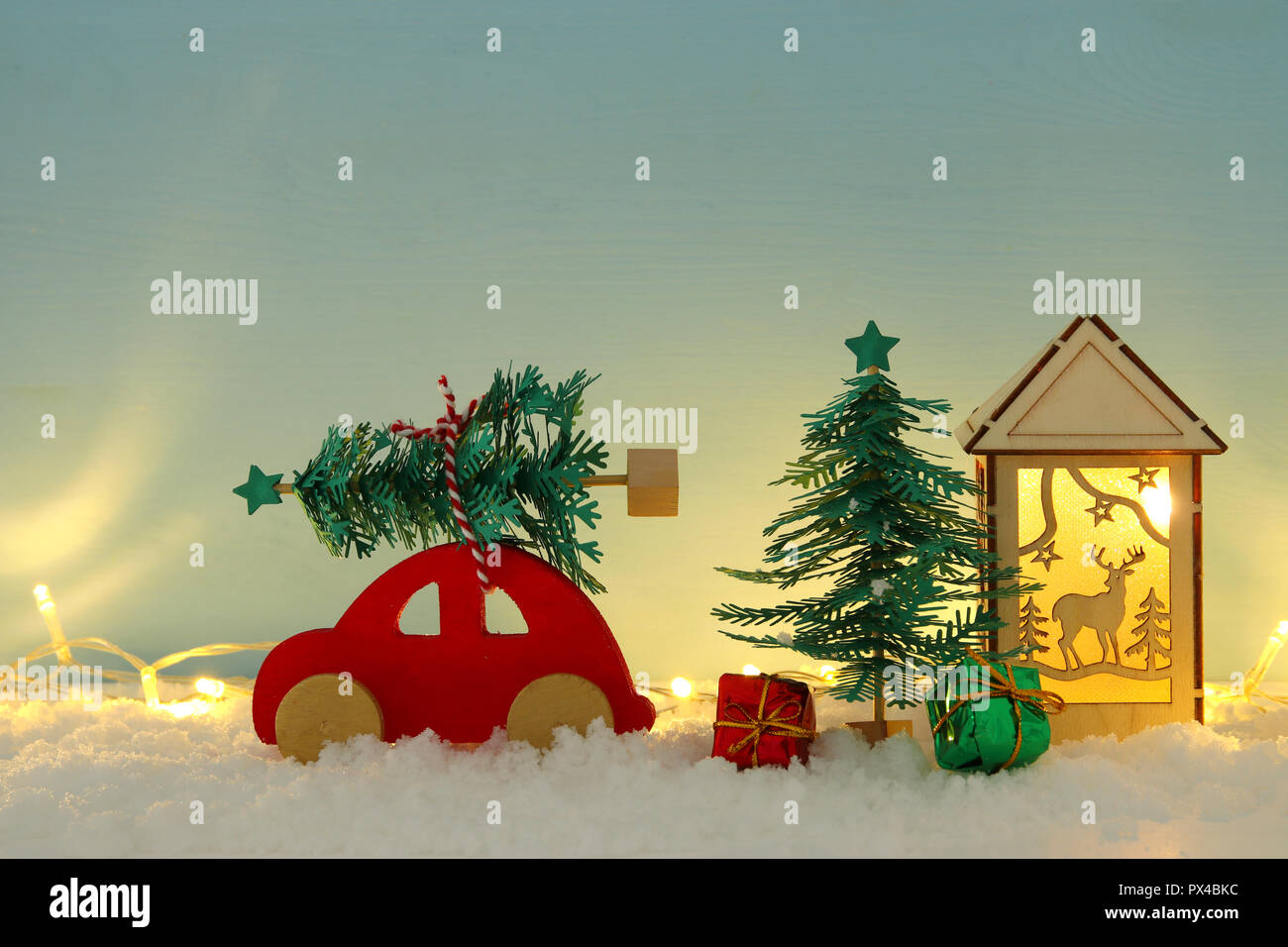 Red wooden car carrying a christmas tree over snow in front of blue ...