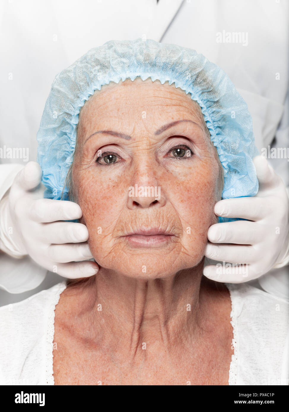 The surgeon doing skin check on mid age woman before plastic surgery ...