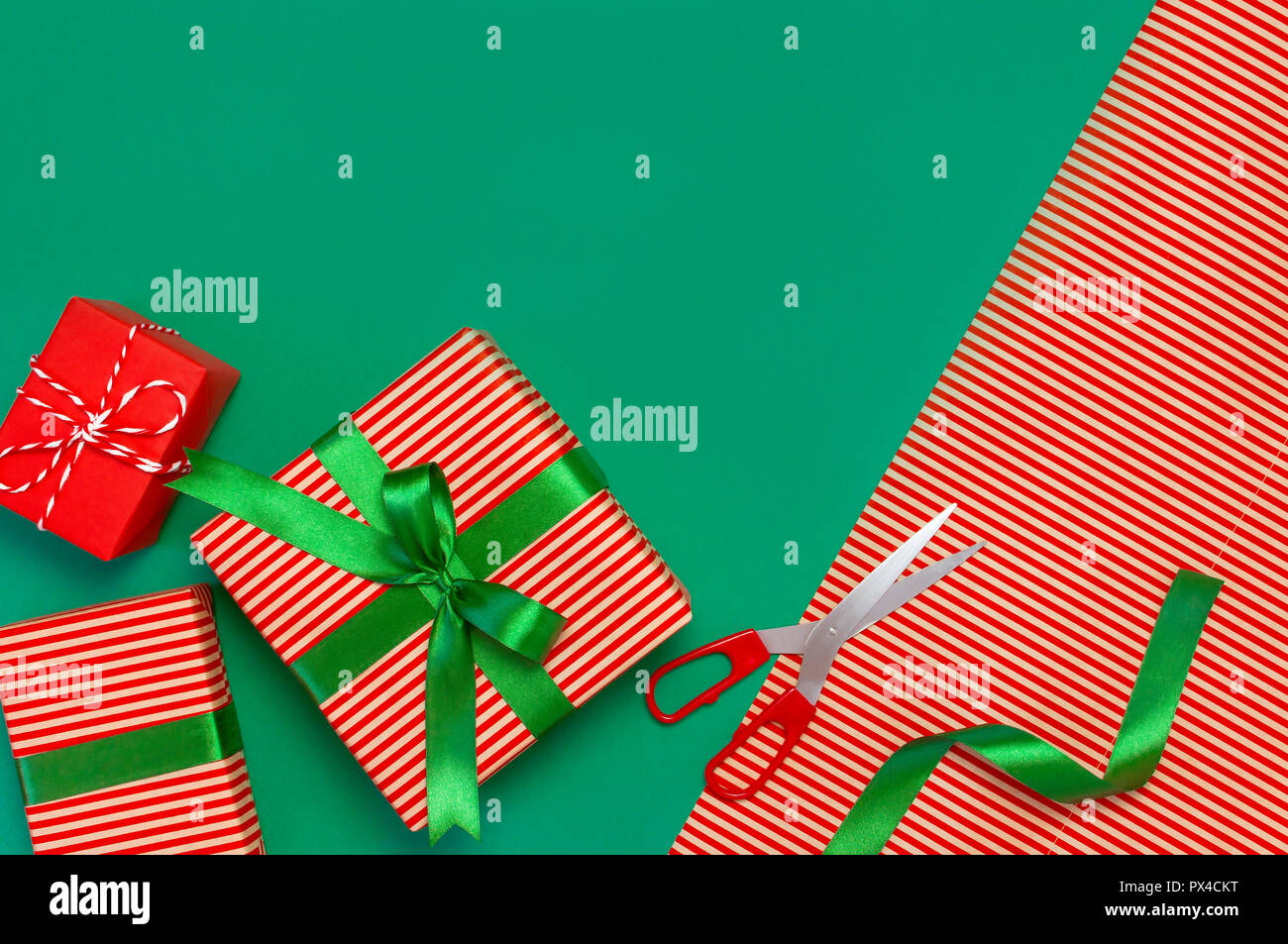 Gift boxes, packing paper, scissors, ribbon on green background ...