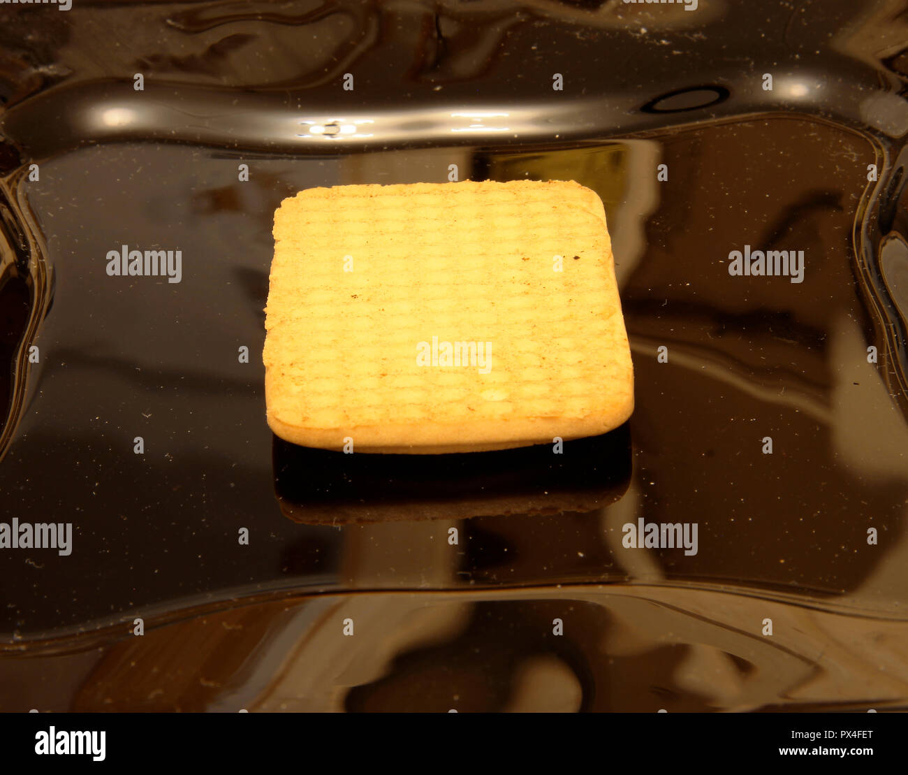 One cookie laying on the black plate Stock Photo - Alamy