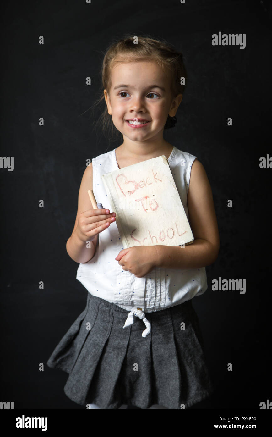Cute hardworking girl schoolgirl with a book in hands on a background ...