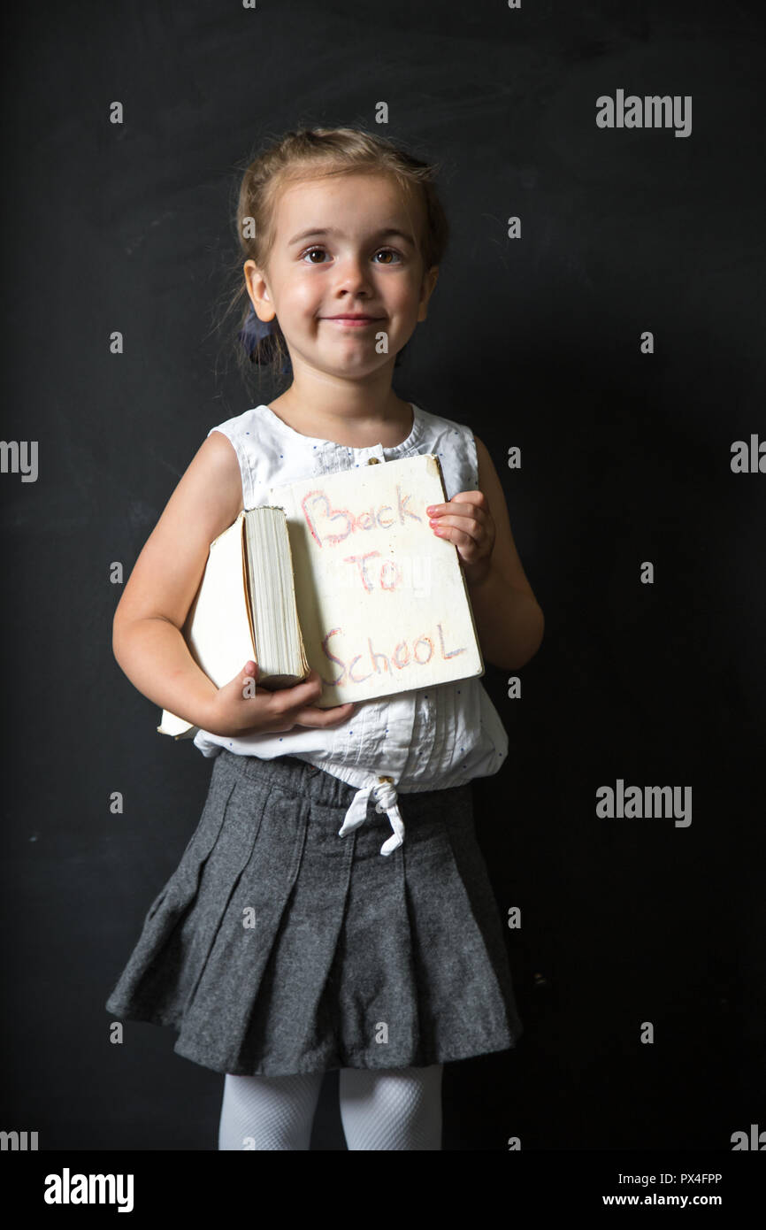 Cute hardworking girl schoolgirl with a book in hands on a background ...