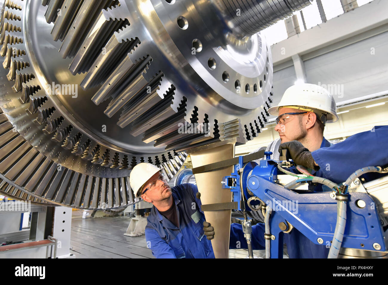 workers assembling and constructing gas turbines in a modern industrial ...