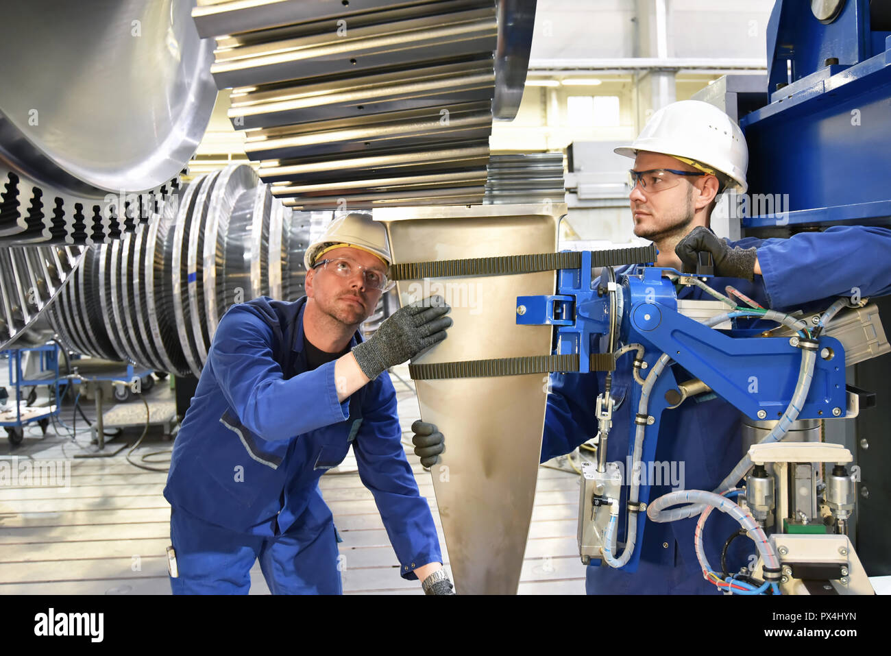 Teamwork - workers manufacturing steam turbines in an industrial ...