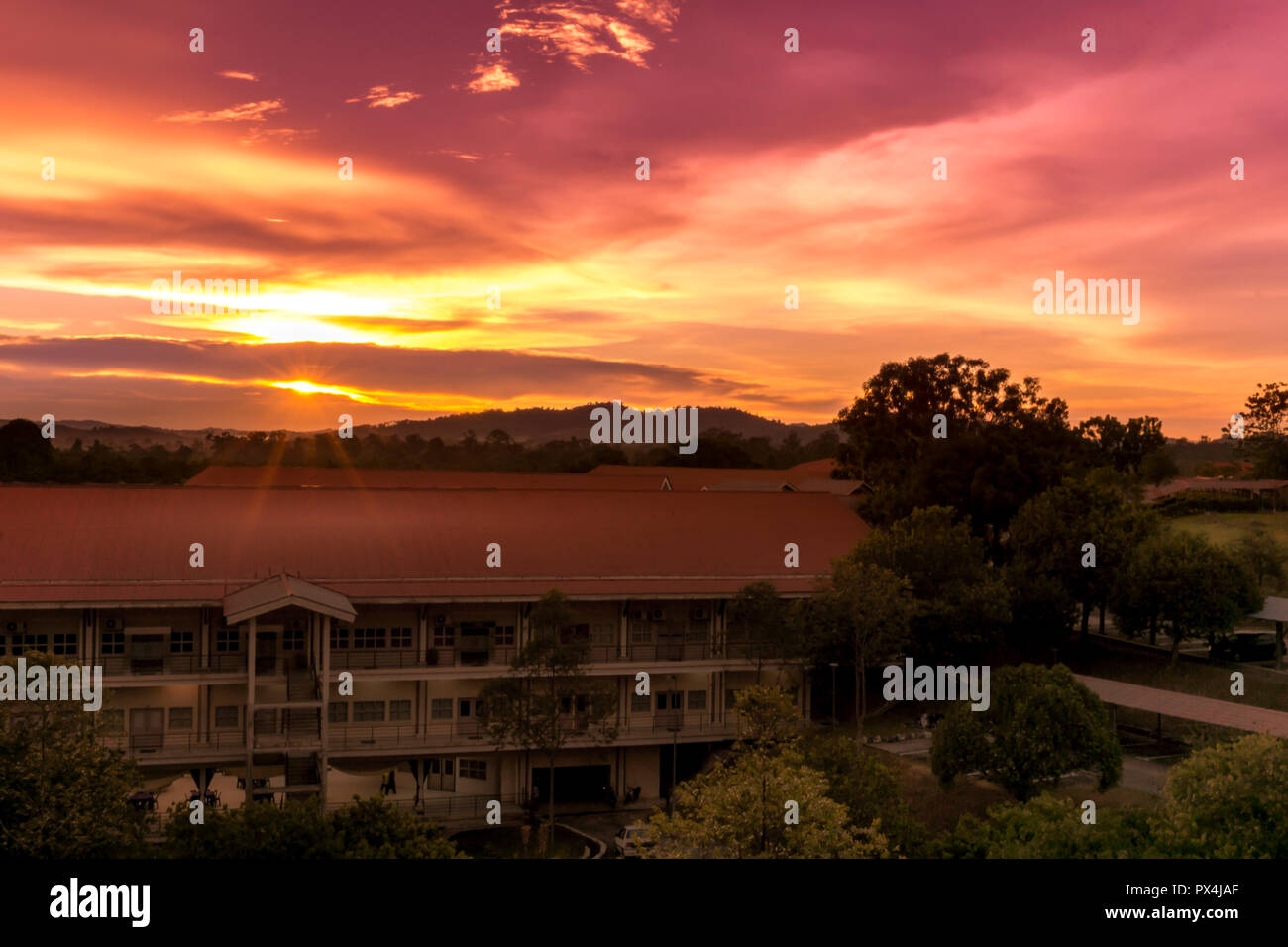 Beautiful sunset above buildings and between mountains Stock Photo - Alamy