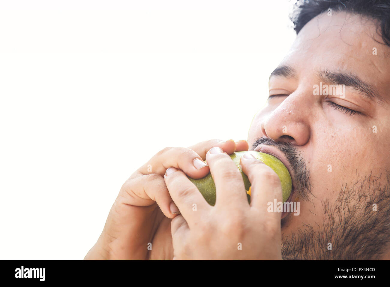 Indian man eating mango on white background Stock Photo - Alamy