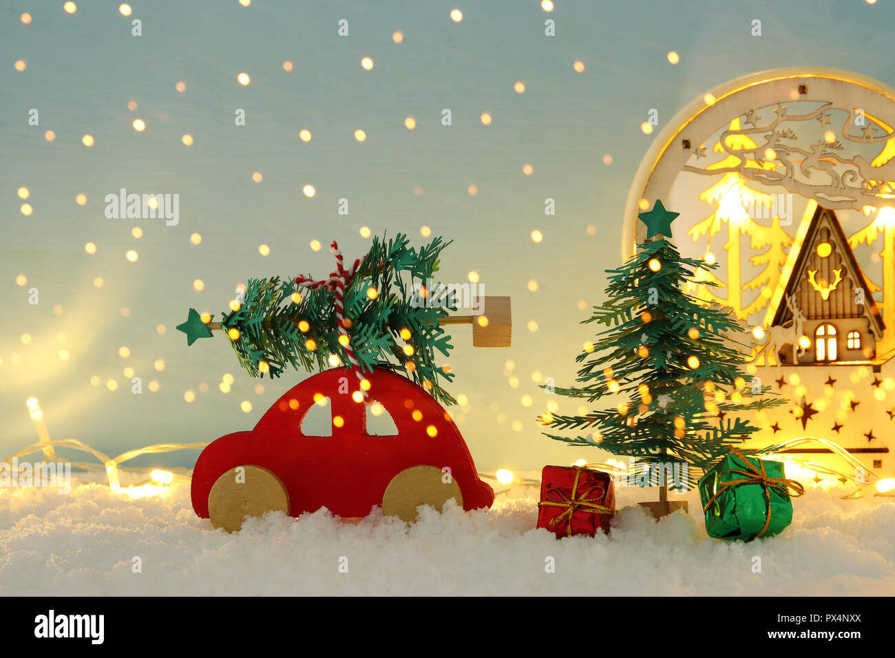 Red wooden car carrying a christmas tree over snow in front of blue ...