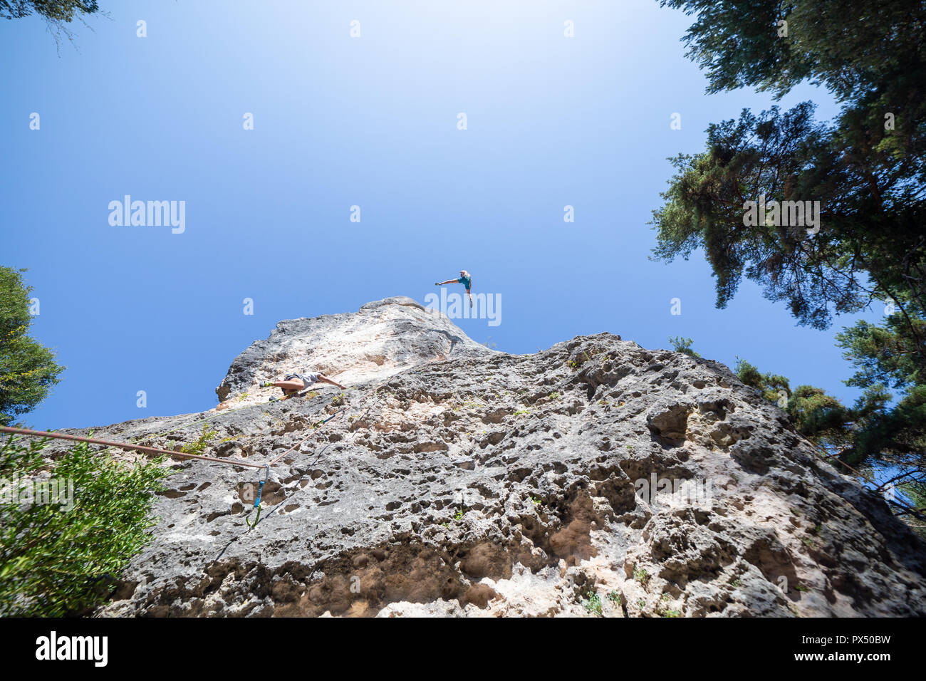 From below shot of climber secured with rope jumping from top of ...