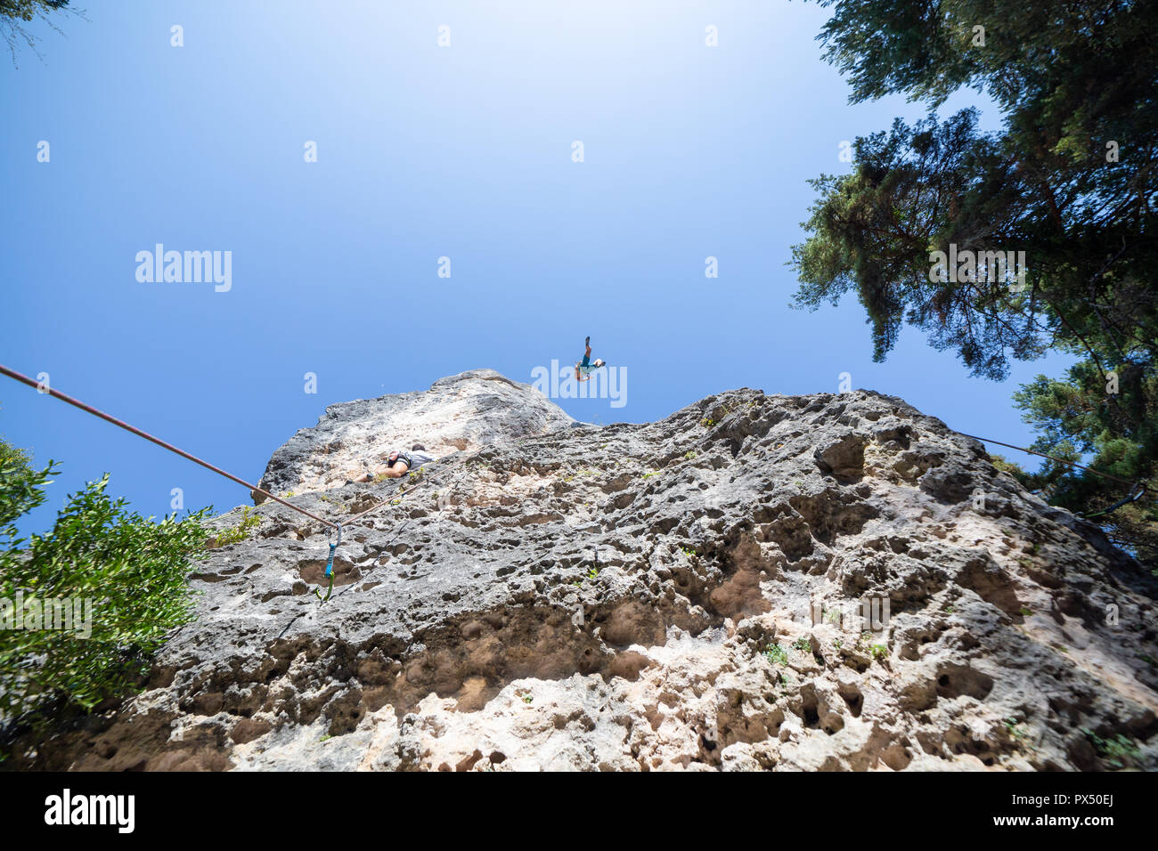 From below shot of climber secured with rope jumping from top of ...