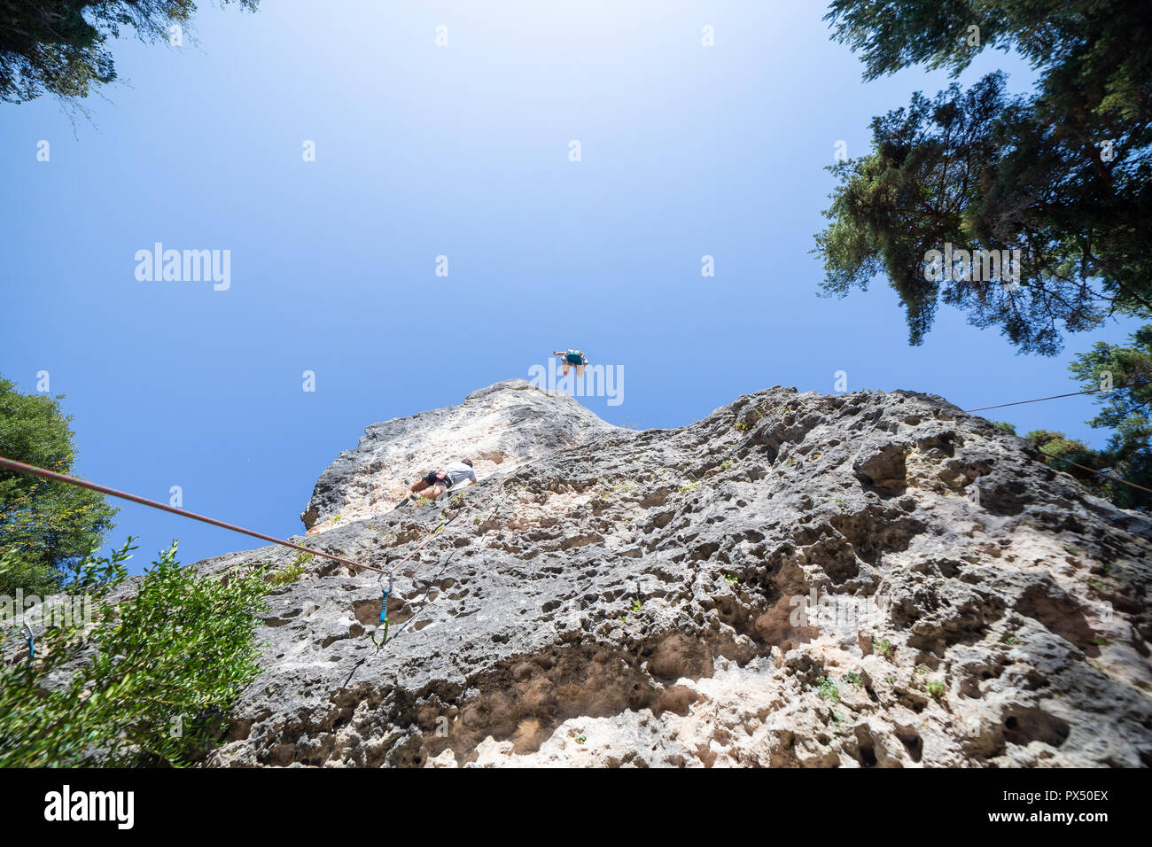 From below shot of climber secured with rope jumping from top of ...