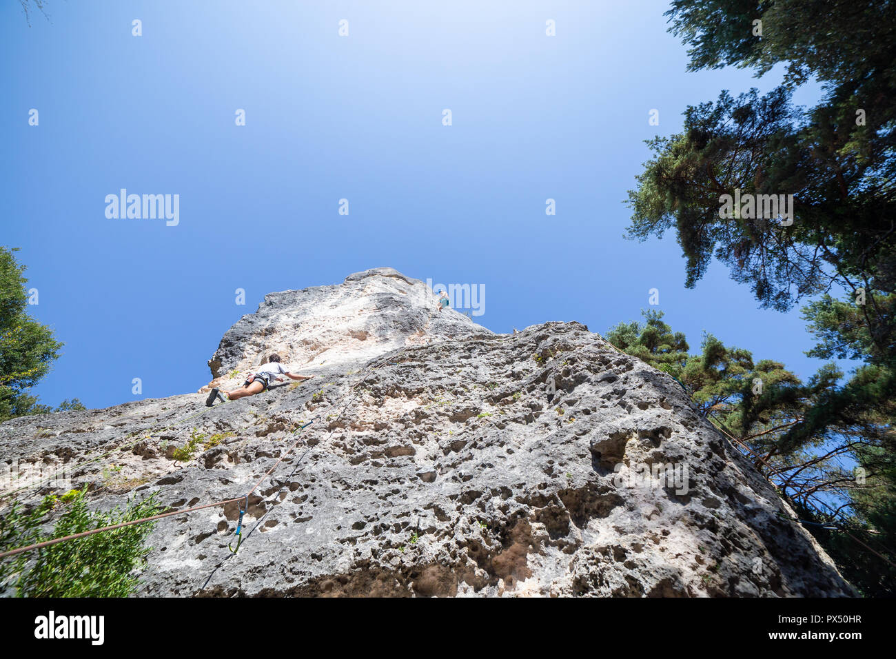 From below shot of climber secured with rope jumping from top of ...