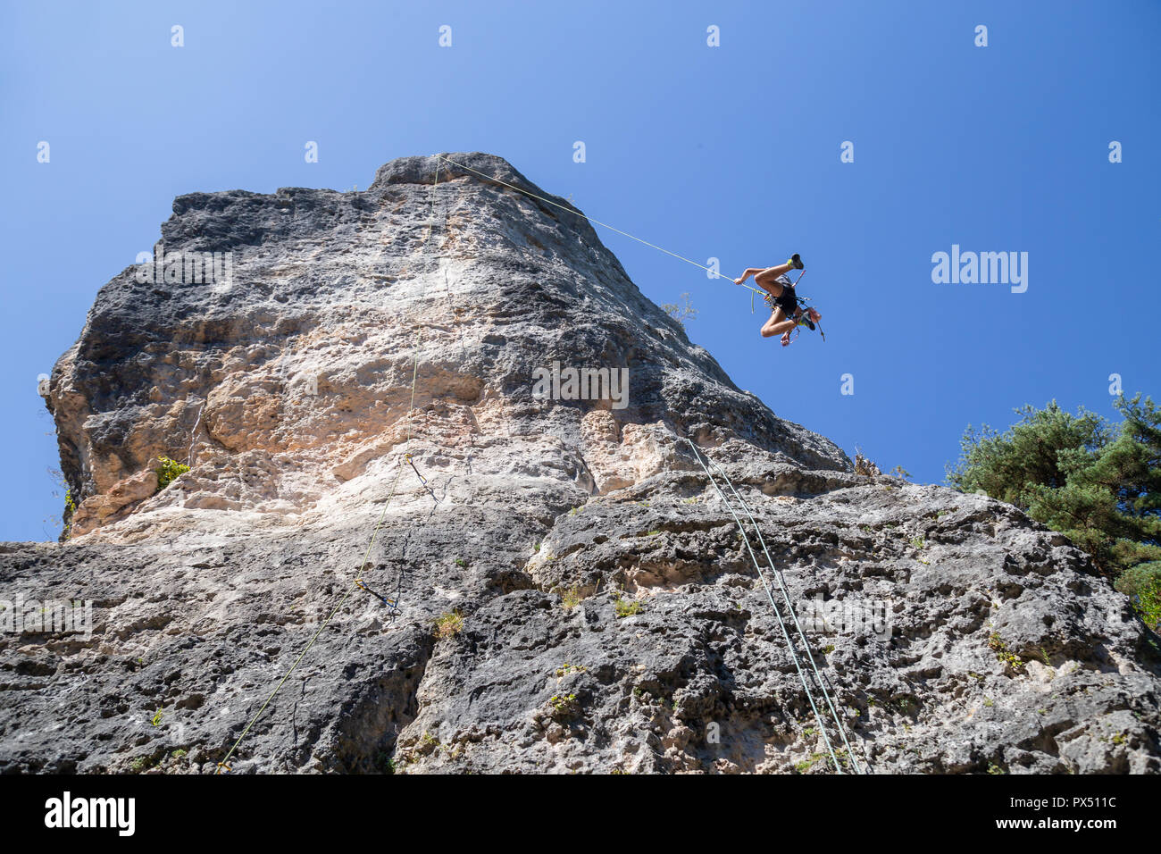 Young man climbing down the mountain doing rappel a sunny day Stock ...