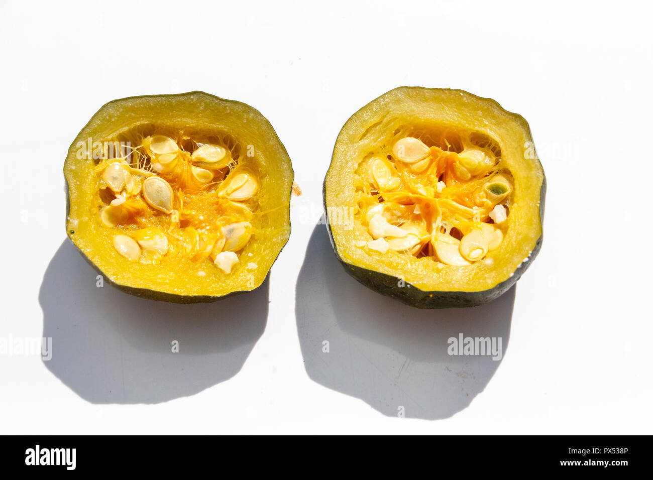 A close up view of two halfs of a open green gem squash with the seeds ...