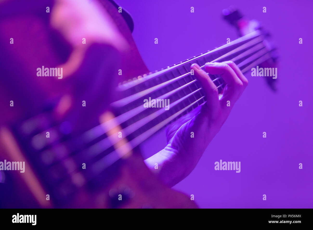 A base guitar player playing an electric base Stock Photo - Alamy