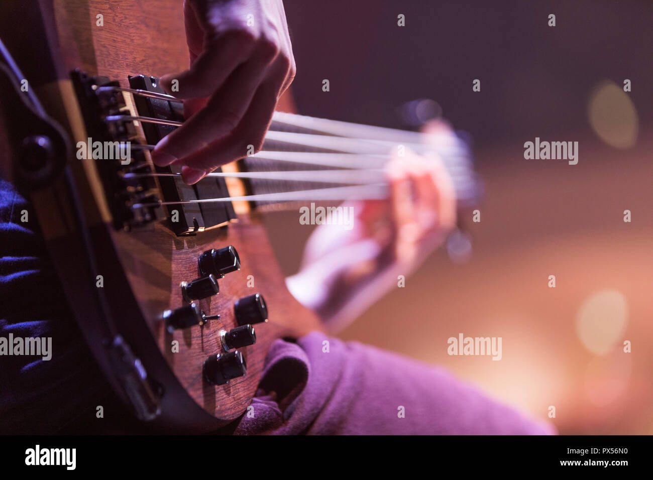 A base guitar player playing an electric base Stock Photo - Alamy