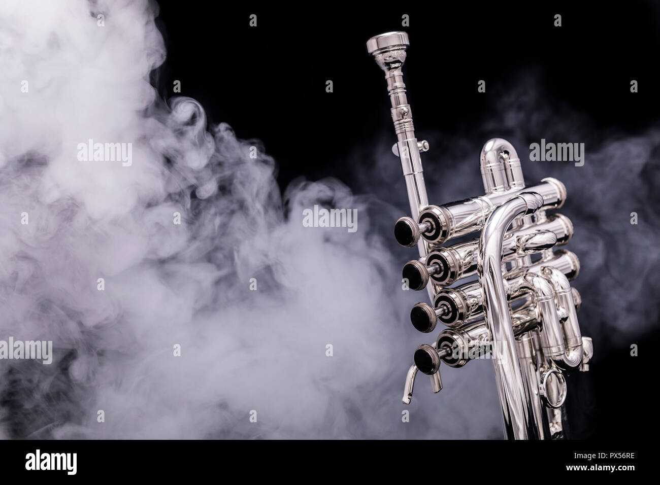 A silver plated piccolo trumpet in smoke on a black background Stock ...