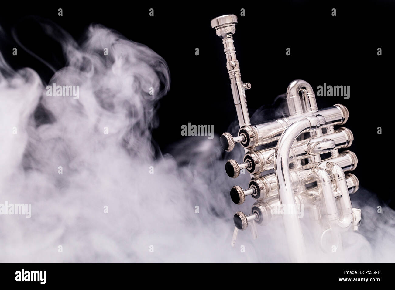 A silver plated piccolo trumpet in smoke on a black background Stock ...