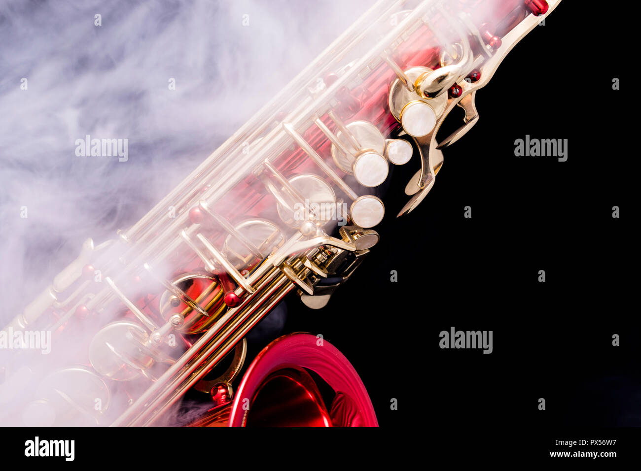 A red lacquered saxophone with gold plated keys in smoke on a black ...