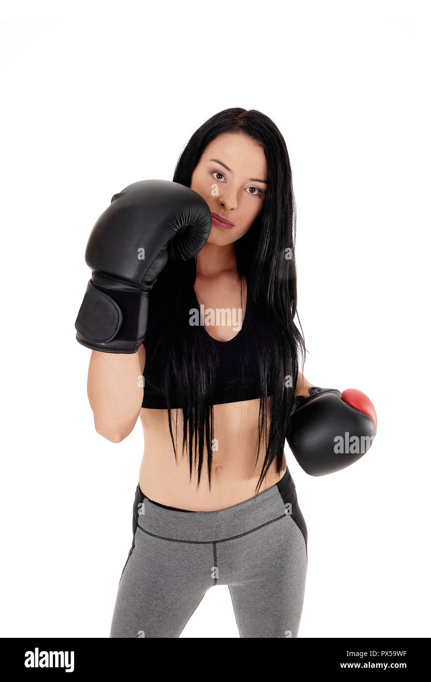 A slim young woman in sportswear and black boxing cloves standing with ...