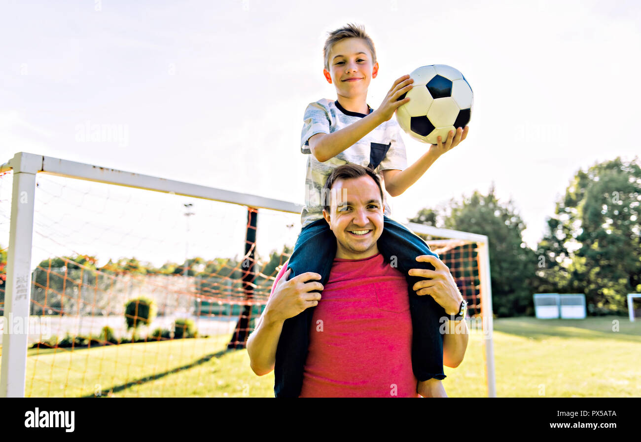 man with child playing football outside on field Stock Photo - Alamy