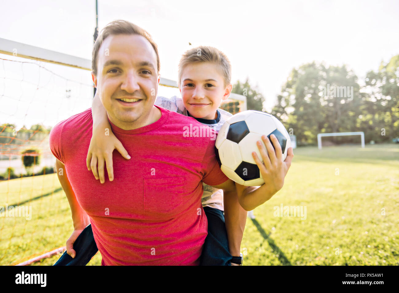 man with child playing football outside on field Stock Photo - Alamy